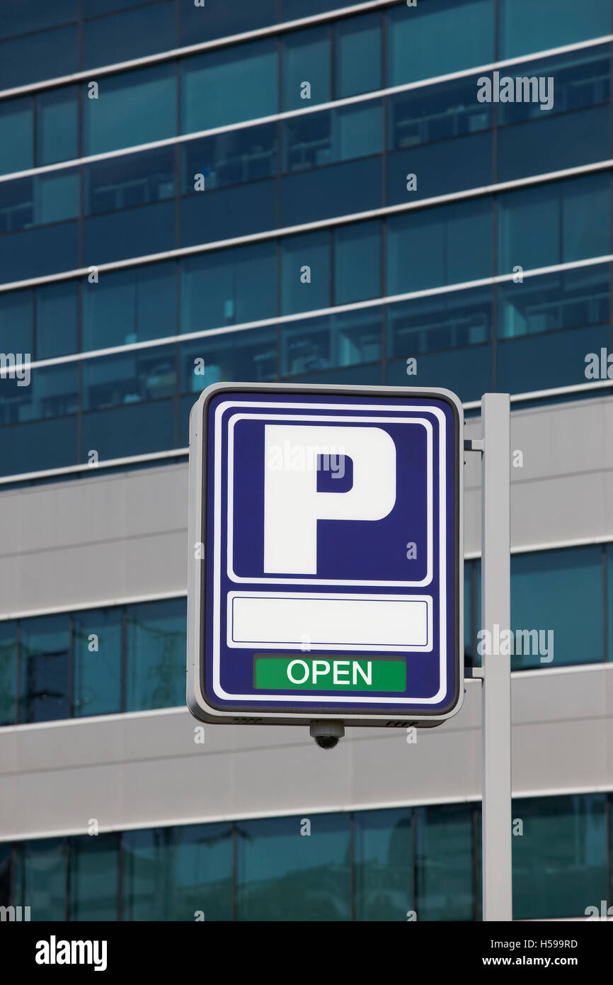 Parking signpost with open text and modern building background ...