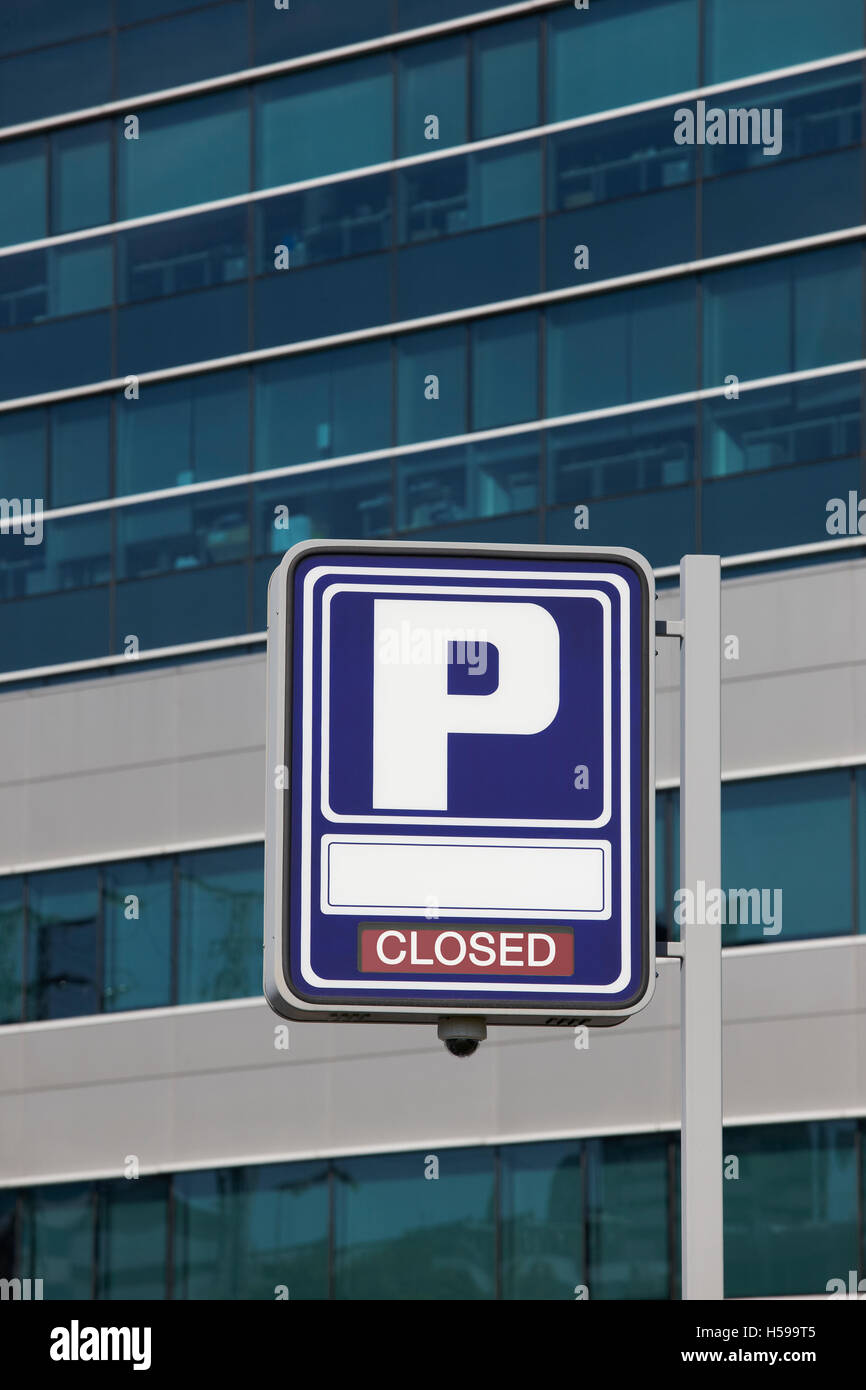Parking signpost with closed text and modern building background ...