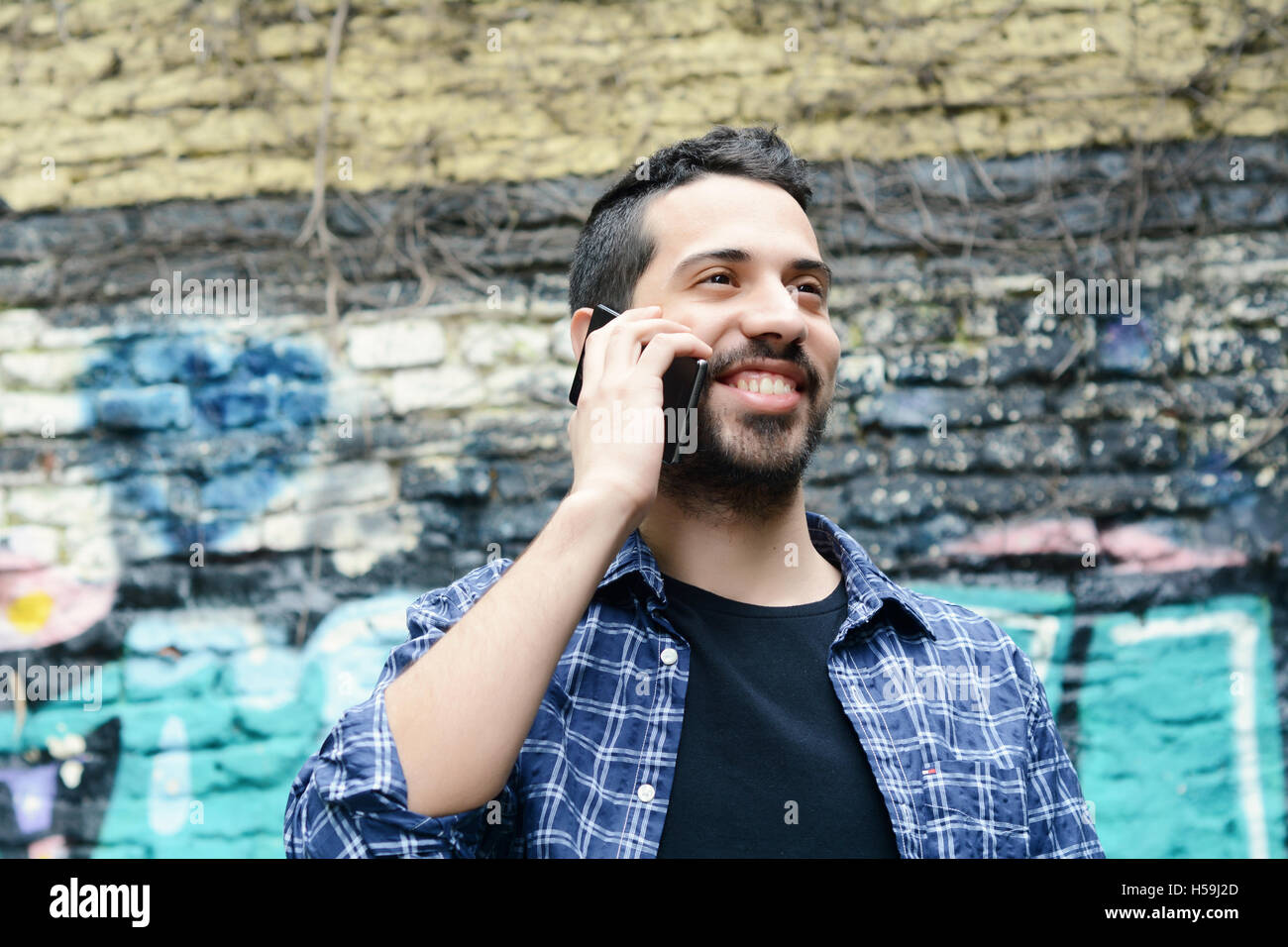 Handsome young latin man talking on the phone. Trendy and urban scene ...