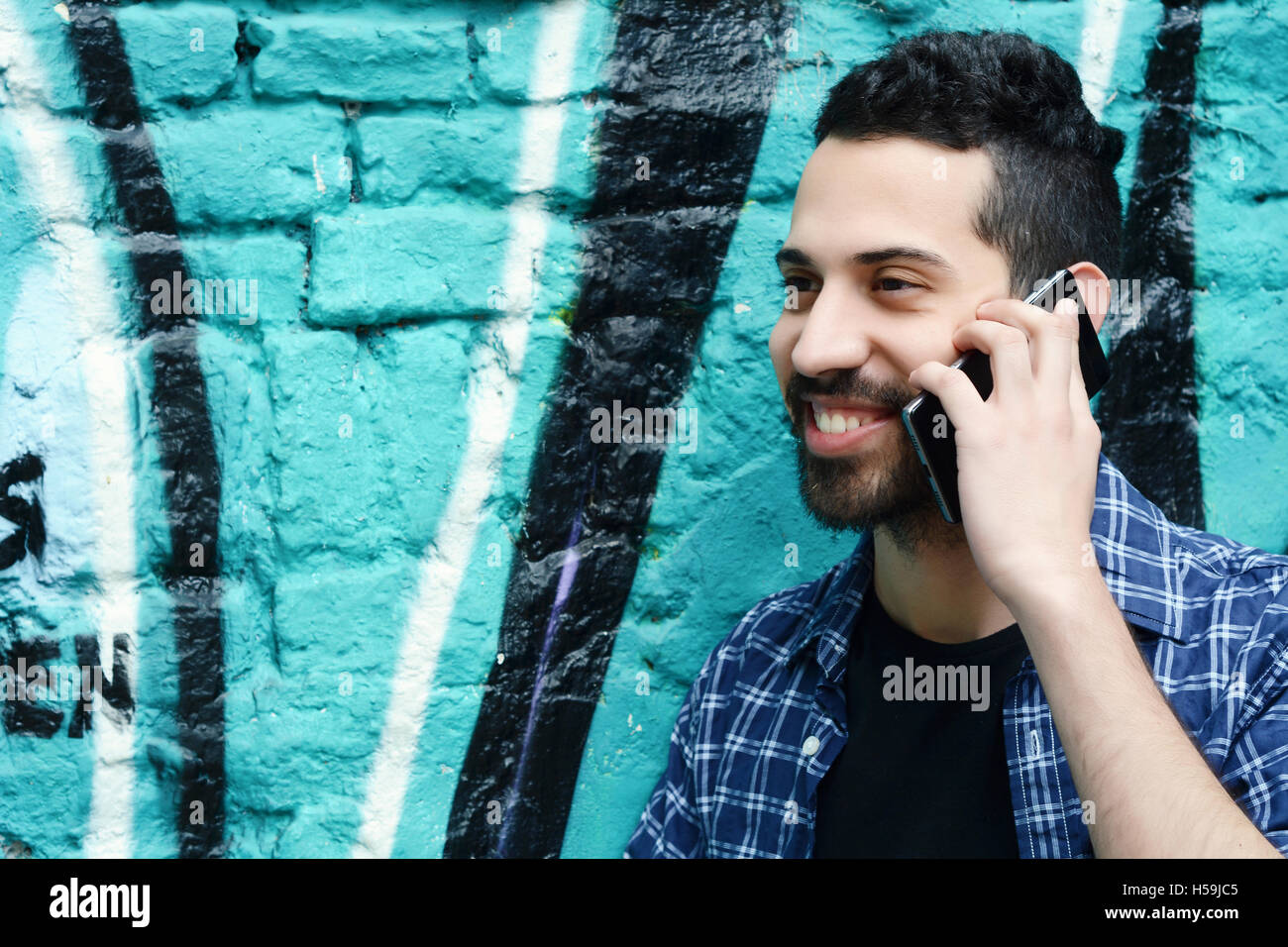 Handsome young latin man talking on the phone. Trendy and urban scene ...
