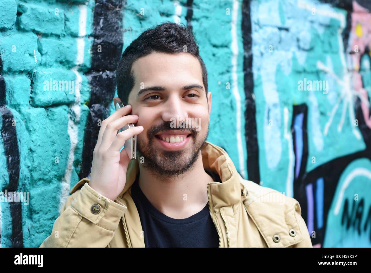 Handsome young latin man talking on the phone. Trendy and urban scene ...