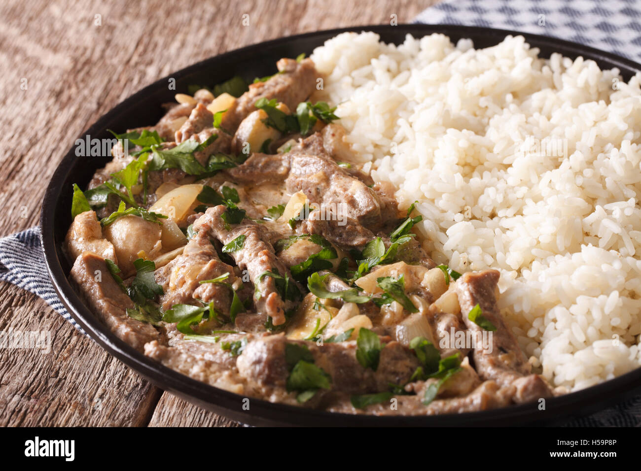 beef stroganoff garnished with rice close-up on a plate on the table ...