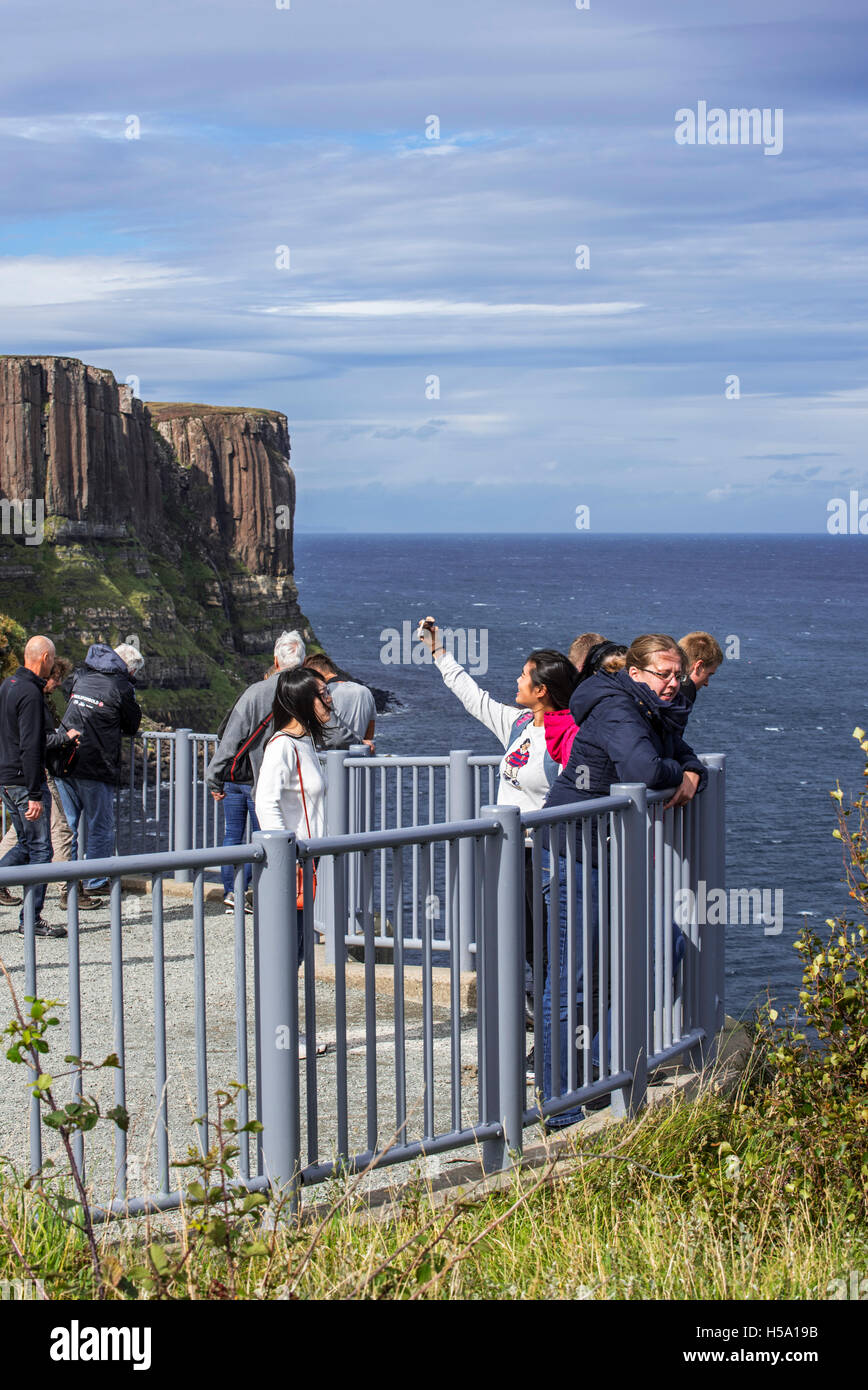 Tourists at viewpoint looking at Mealt waterfall at Kilt Rock, sea ...