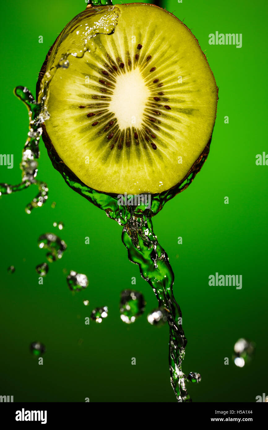 Kiwi in water splash, isolated on green background Stock Photo - Alamy