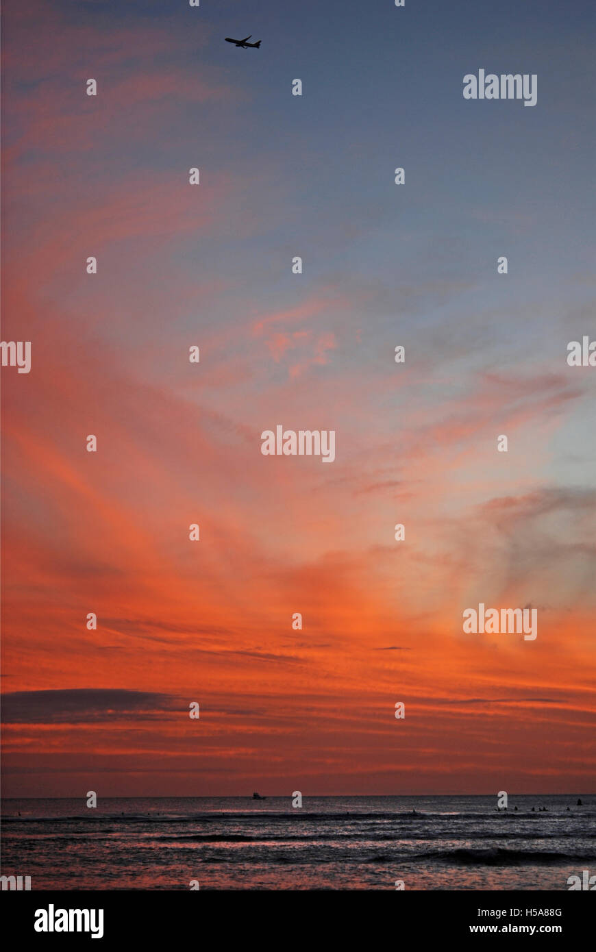 Airplane flying in spectacular sunset sky over Waikiki beach in ...