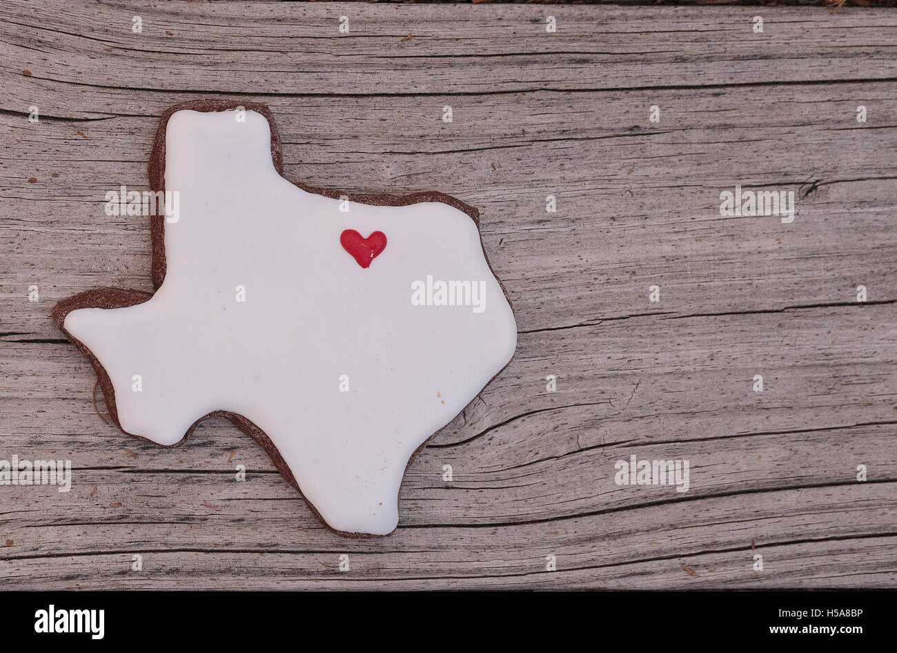 Texas shaped sugar cookie with white icing and a red heart on a rustic ...