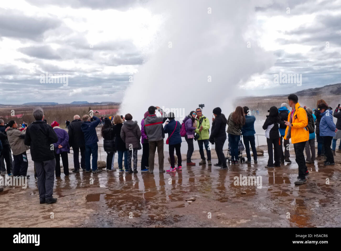 Tourists looking at hot spring eruption at Geysir, Iceland Stock Photo ...