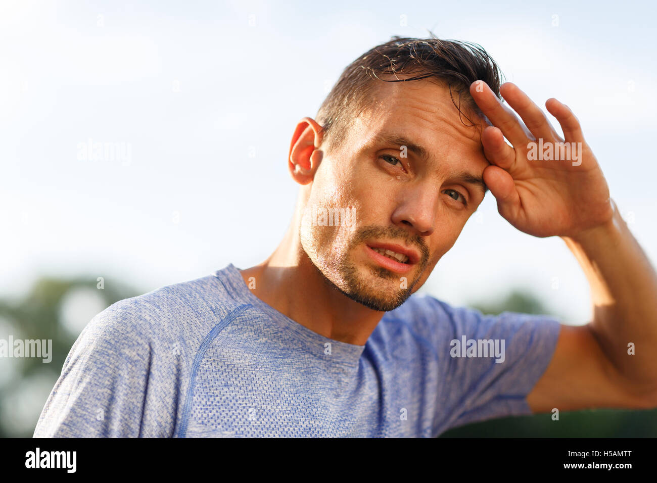 Fit man bent head and wipes forehead with his fingers Stock Photo - Alamy