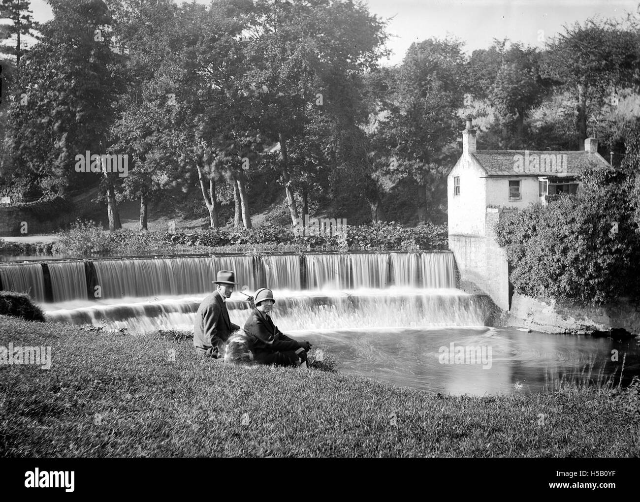 Two couples are seated by the River Dodder, near a weir, capturing a ...