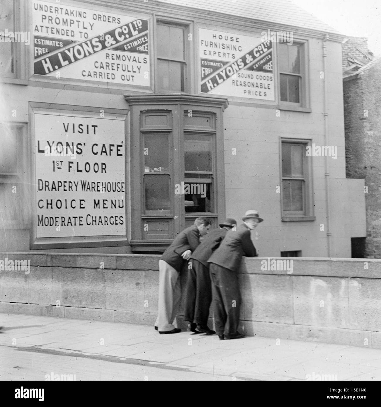 A photo featuring three men at a bridge with advertisements on the wall ...