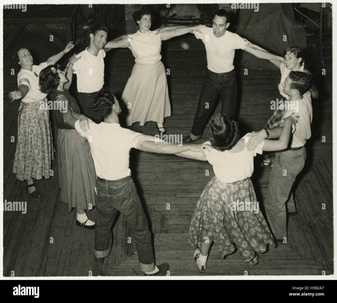 This image captures young men and women dancing in a circle, likely ...