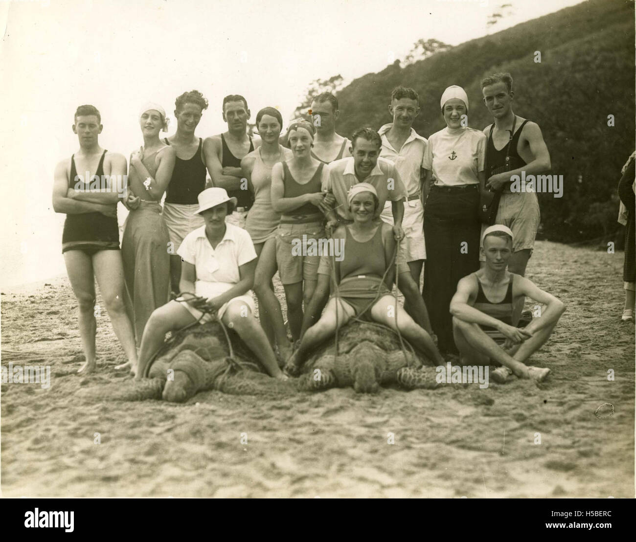 Two tourists are seen sitting on sea turtles on a sandy beach, likely ...
