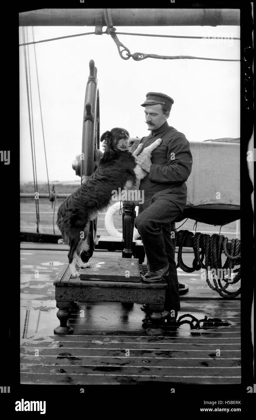A photograph of a ship's officer standing with his pet dog at the ship ...