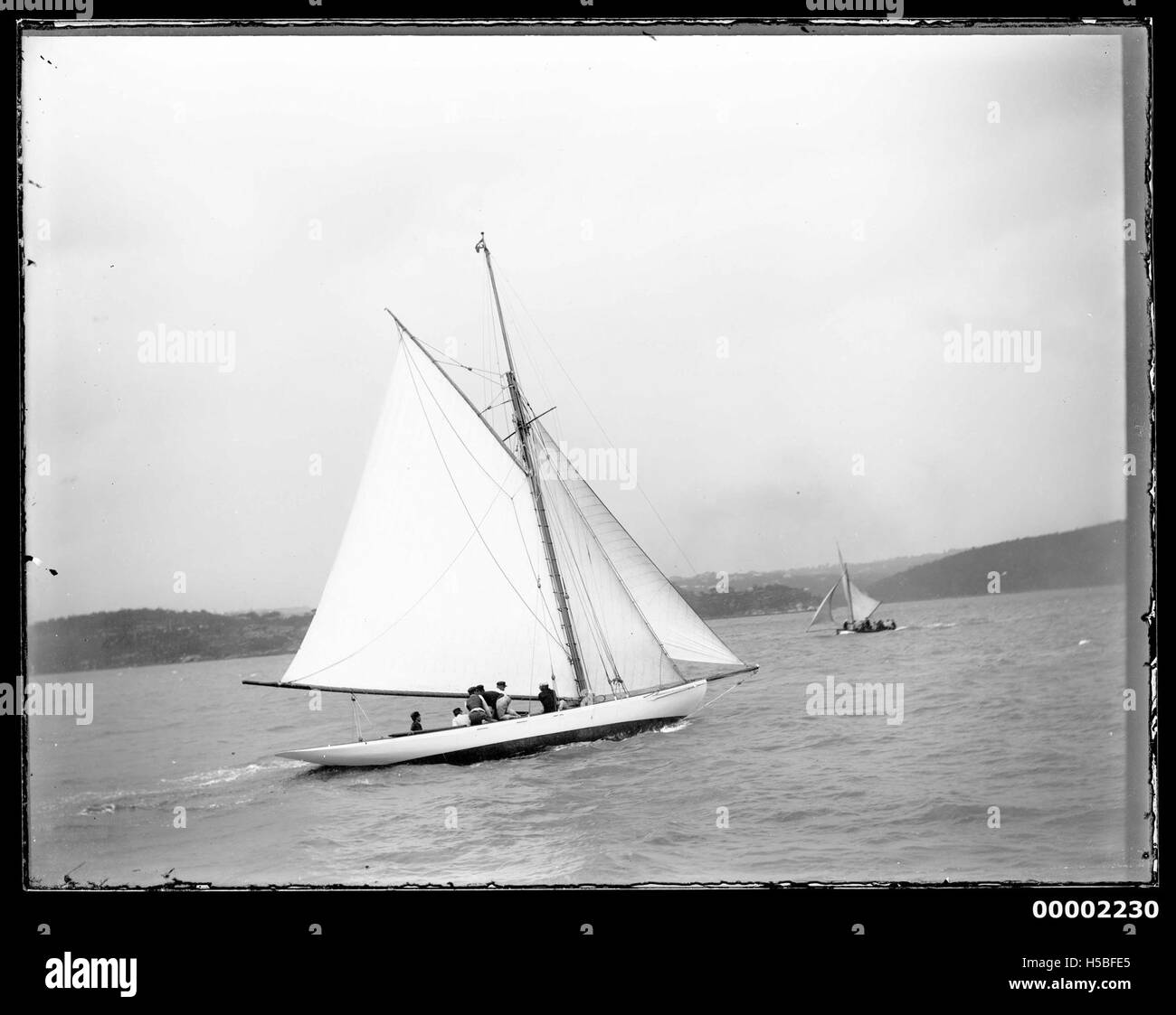 A white-hulled gaff cutter sails through the water, showcasing its ...