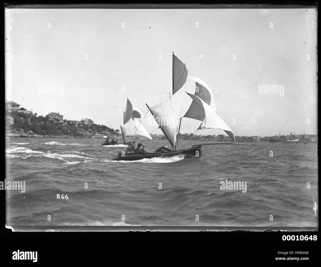 This image shows a 12-foot sailing boat on Sydney Harbour. The boat is ...