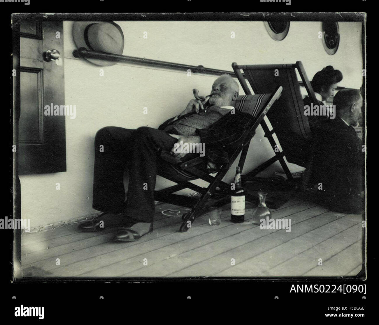 A passenger relaxes on a deck chair, smoking a pipe, possibly aboard a ...