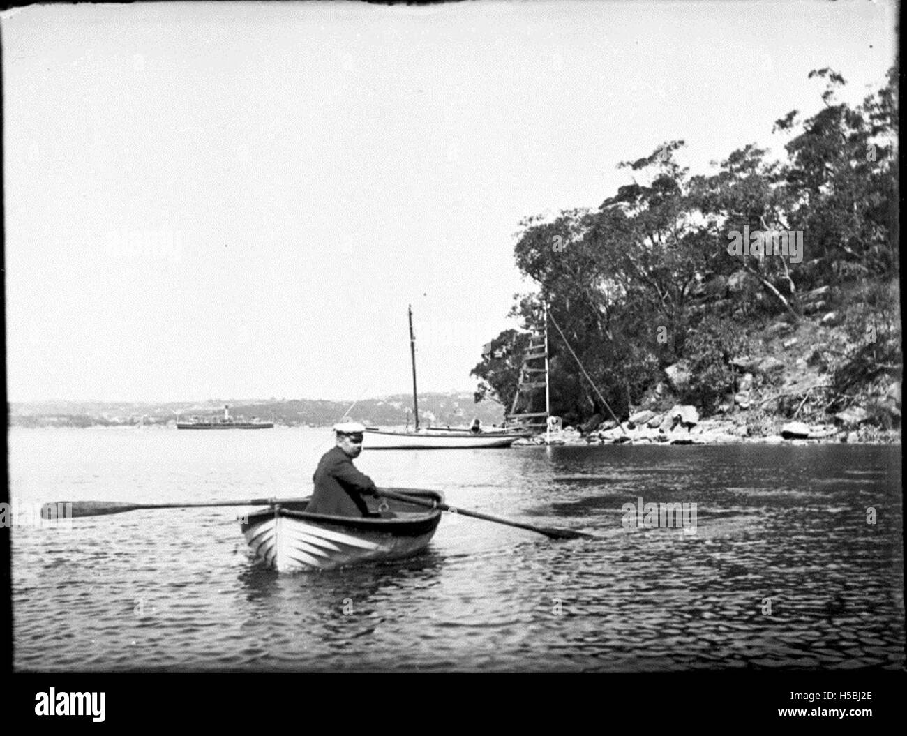 A photograph showing a man rowing a small boat from his yacht ...