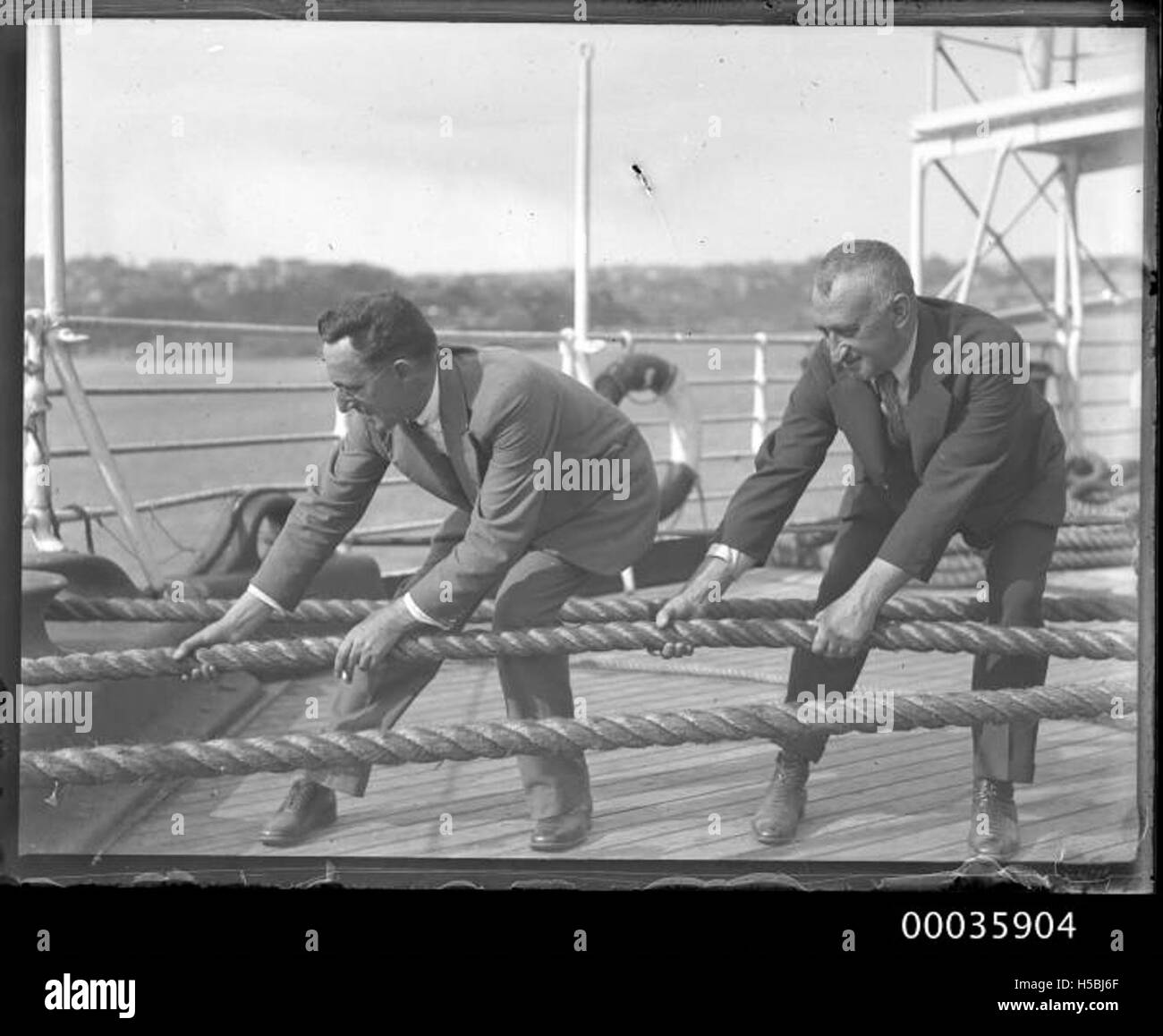Two men are shown pulling ropes on the deck of the SS Runic during the ...
