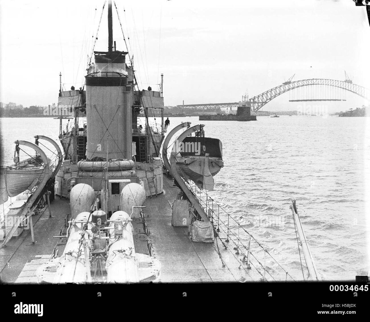 A view of the unfinished Sydney Harbour Bridge taken aboard HMAS ANZAC ...