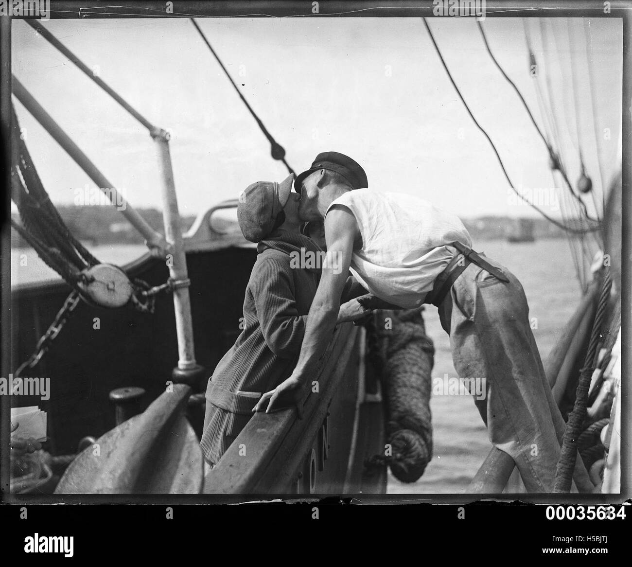 This photograph from 1920-1939 shows a man and woman kissing across two ...