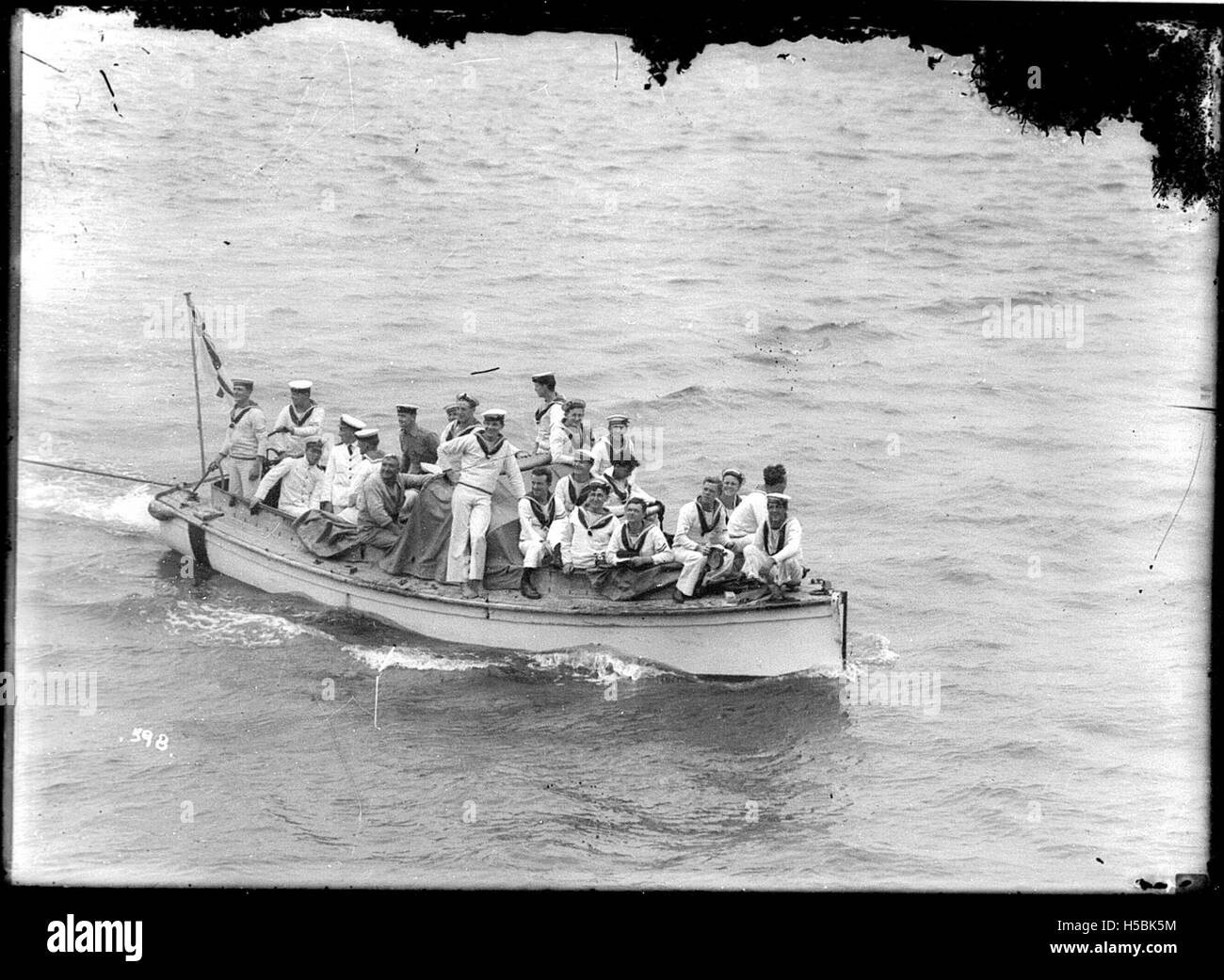 This image shows a naval launch and sailors aboard a vessel in a harbor ...
