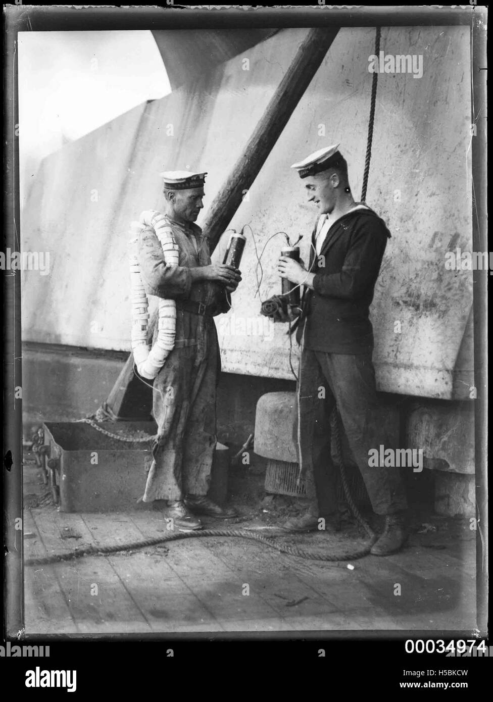 Sailors aboard HMAS AUSTRALIA are seen with demolition charges, likely ...