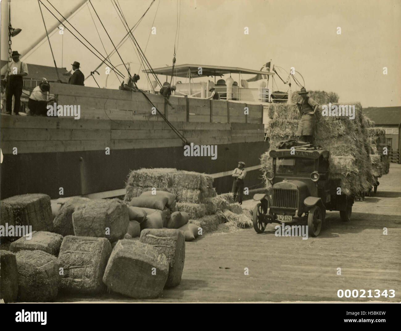 This image shows the loading of hay bales onto a Norwegian merchant ...