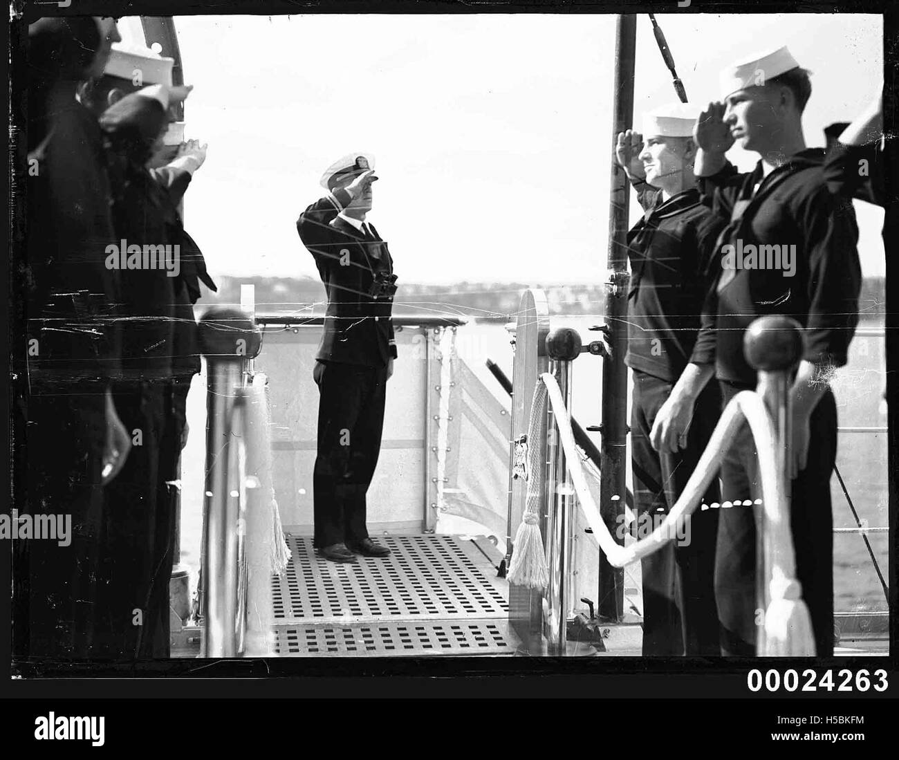 The photograph shows US Naval officers and sailors aboard the USS ...