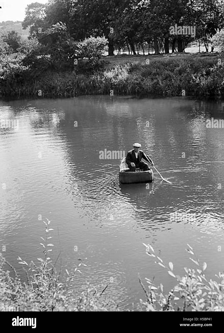 This photograph captures a man navigating a coracle, a traditional ...