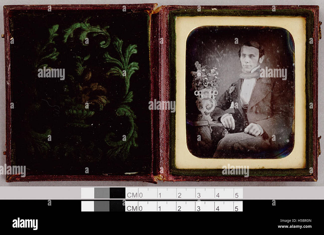 A gentleman is seated next to a vase of flowers, offering a calm and ...