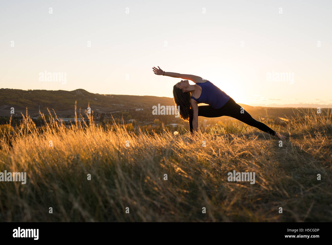 Woman doing yoga extended side angle pose during sunset Stock Photo - Alamy