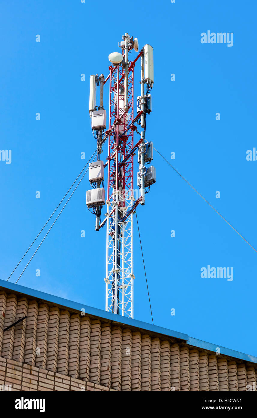 Telecommunication tower for mobile phone with antennas over a blue sky. Distribution function of ...