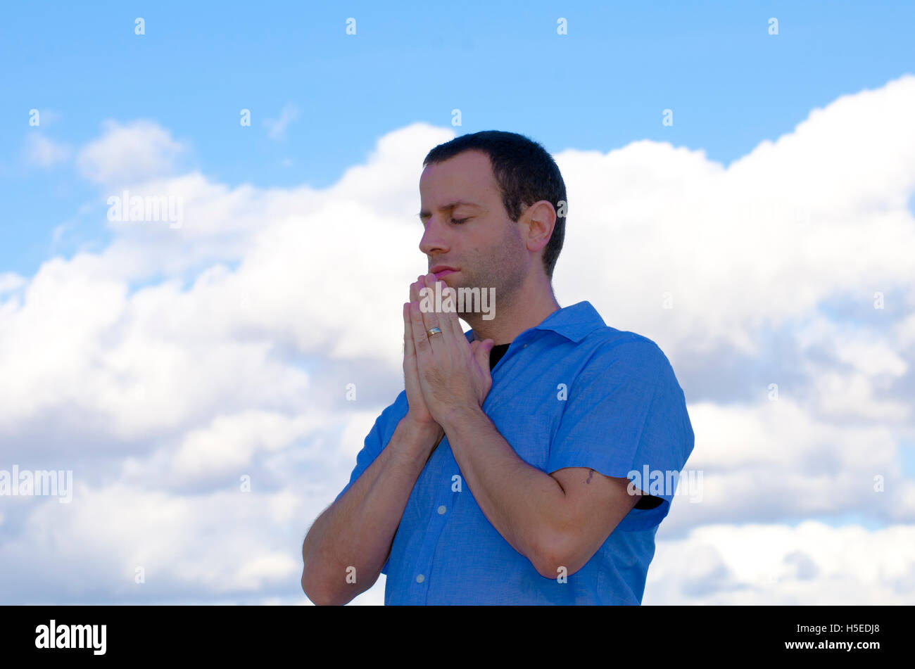 Man praying with the clouds in the background Stock Photo - Alamy