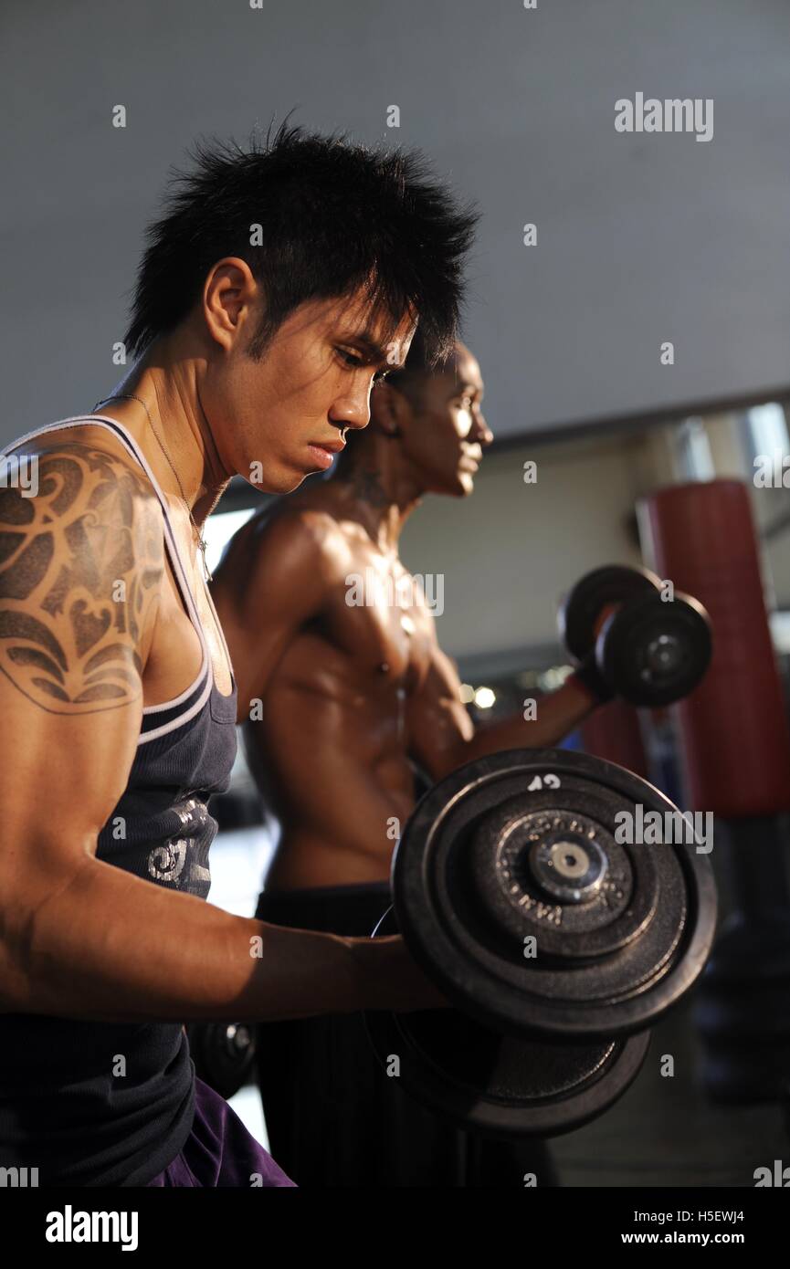 Asiatic man in the gym performing an exercise arm dumbbell curl Stock ...