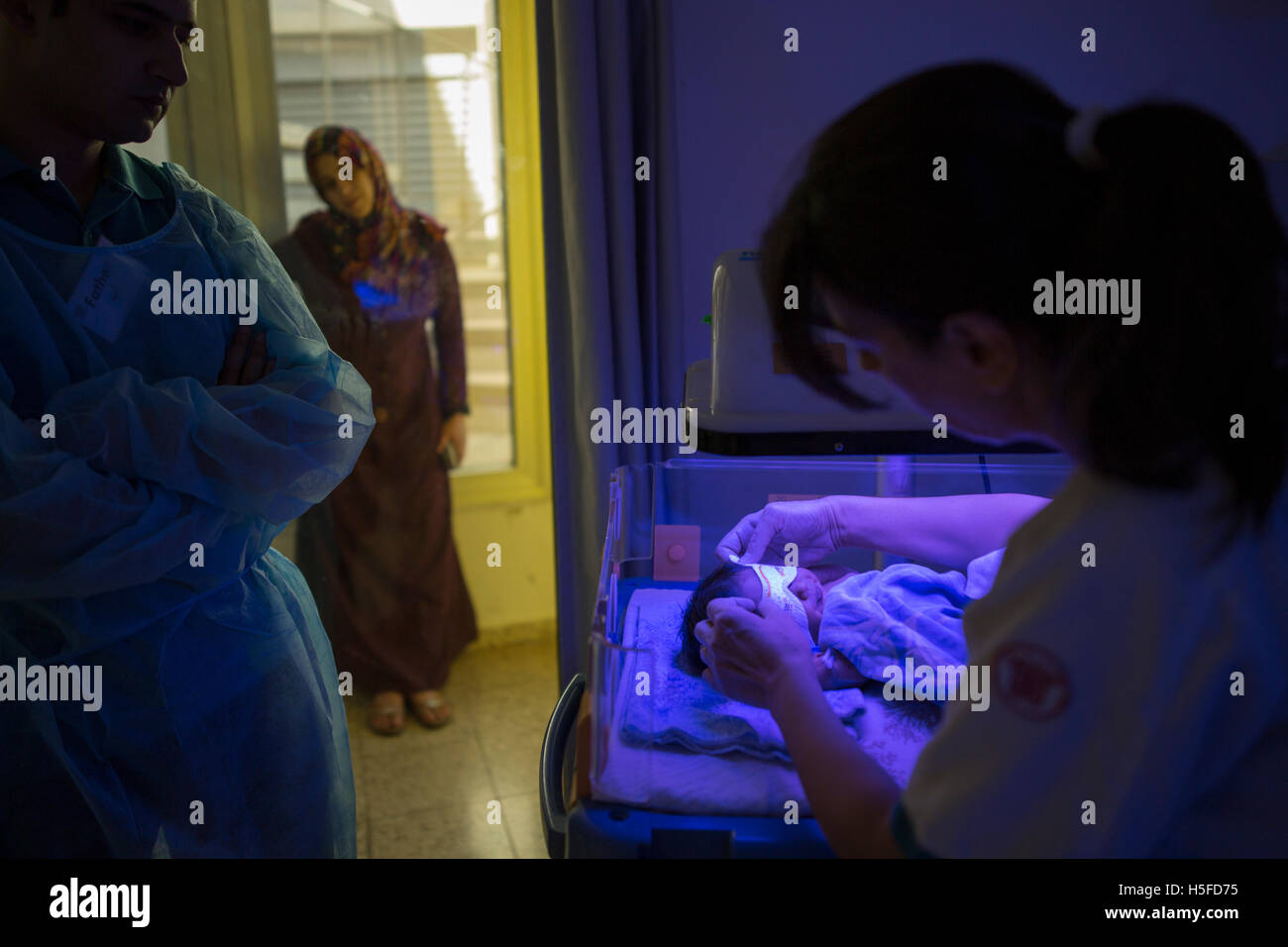 A baby being treated with blue light, a jaundice-prevention measure, in ...
