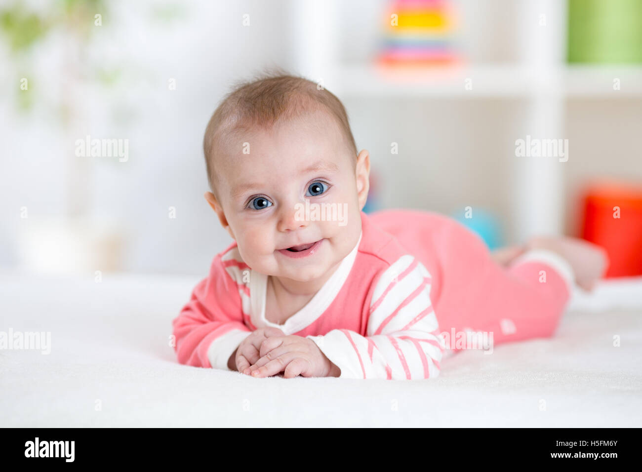 Portrait of pretty baby girl lying on tummy Stock Photo - Alamy