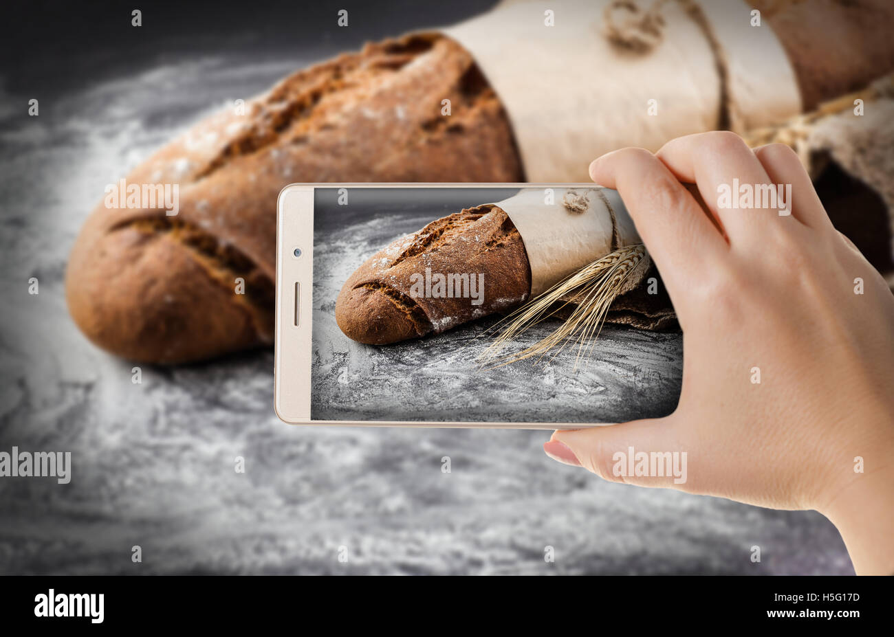Hands with the phone close-up.Woman photographed fresh baked bread to a ...