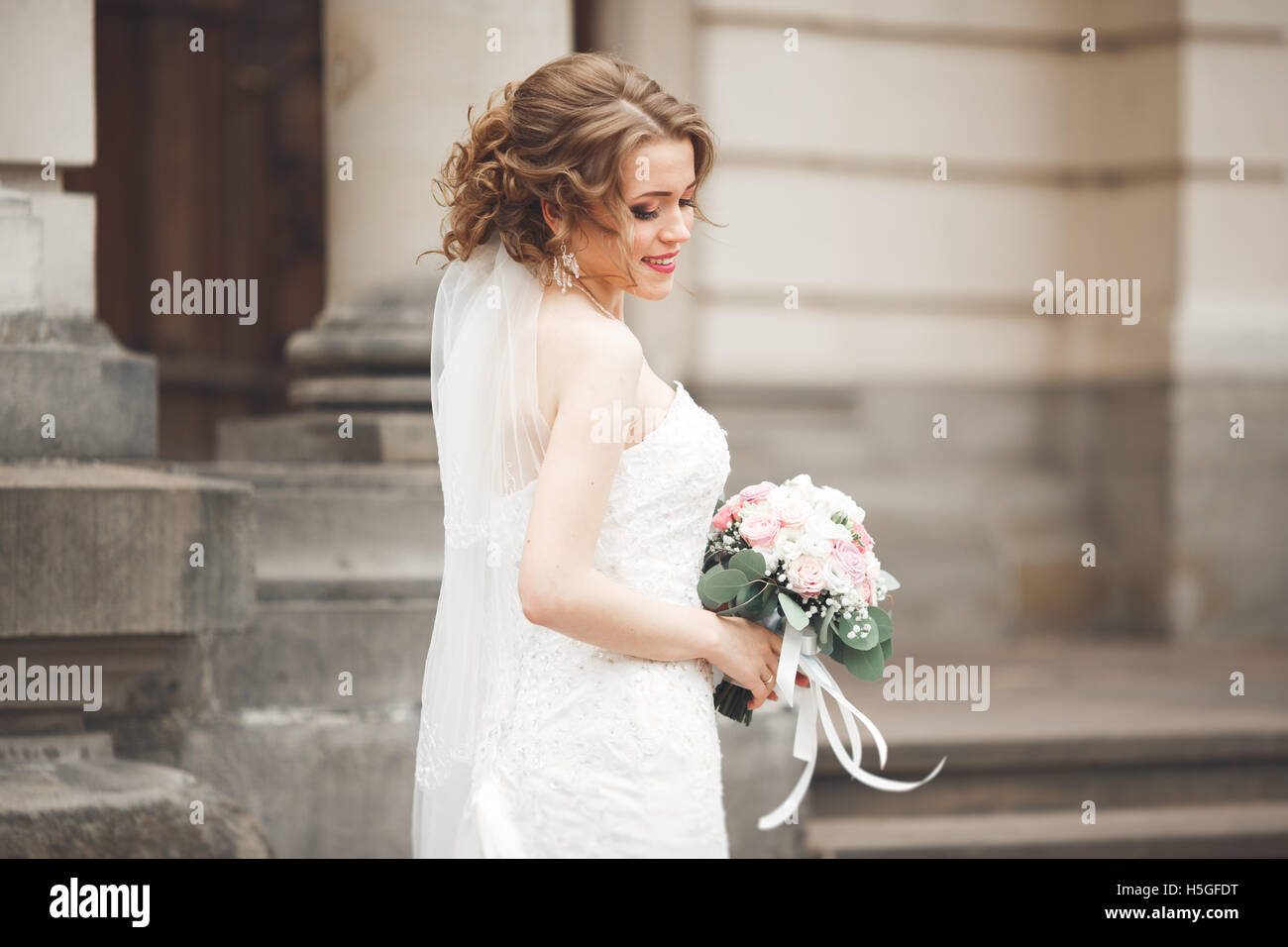 Wonderful bride with a luxurious white dress posing in the old town ...