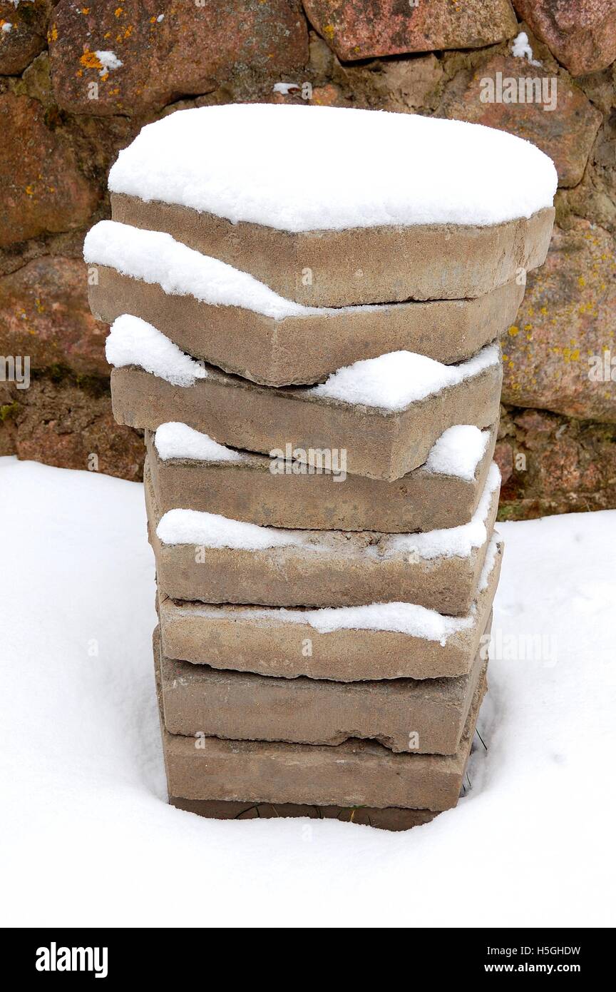 stack from sidewalk plates under snow opposite to a stone wall Stock ...