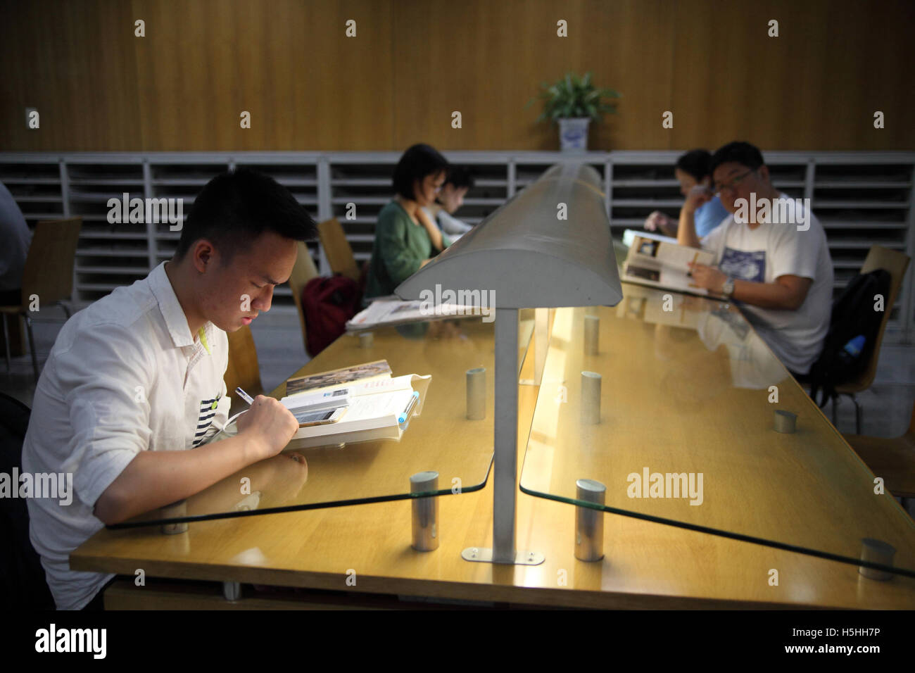 Young Chinese people sit and read in the library. Shenzhen Library ...