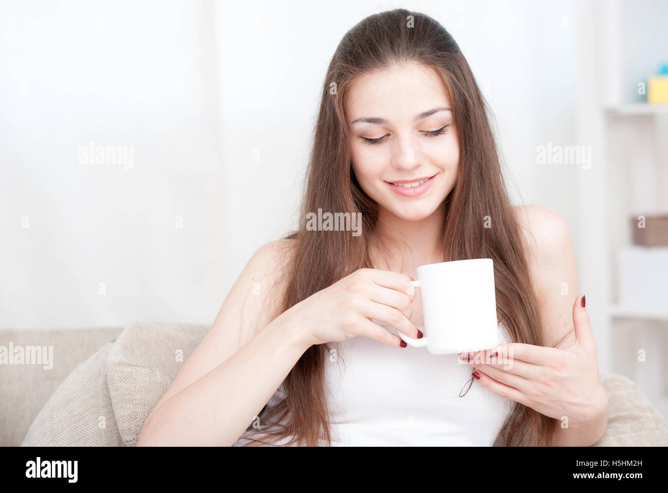 Happy girl on the couch at home in the living room Stock Photo - Alamy