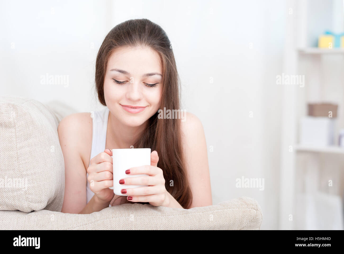 Happy girl on the couch at home in the living room Stock Photo - Alamy
