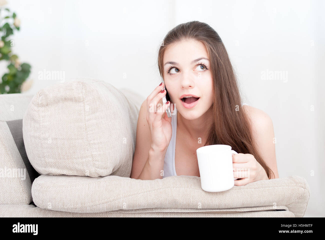 Happy girl on the couch at home in the living room Stock Photo - Alamy