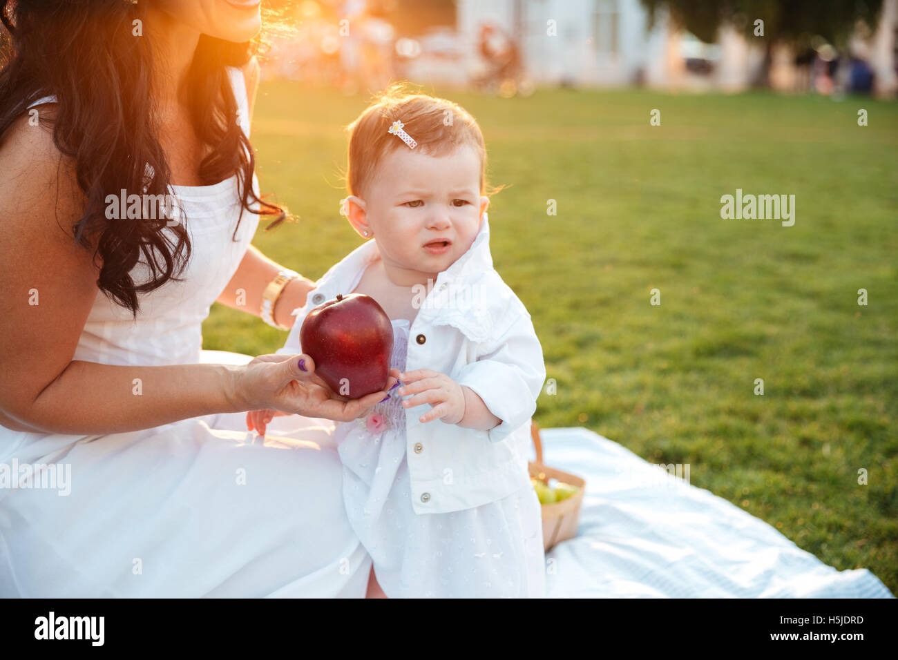 Mother giving fresh red apple to her little daughter in park Stock ...