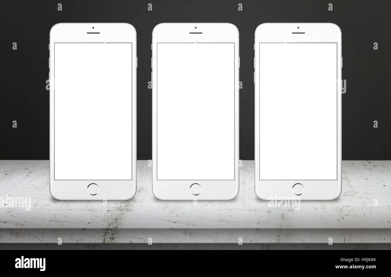 Three white mobile phones on table with blank, white, isolated display ...