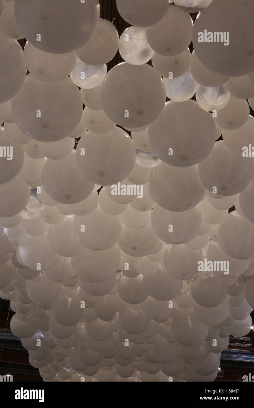 many big white balloons hanging from the ceiling during a ceremony and ...