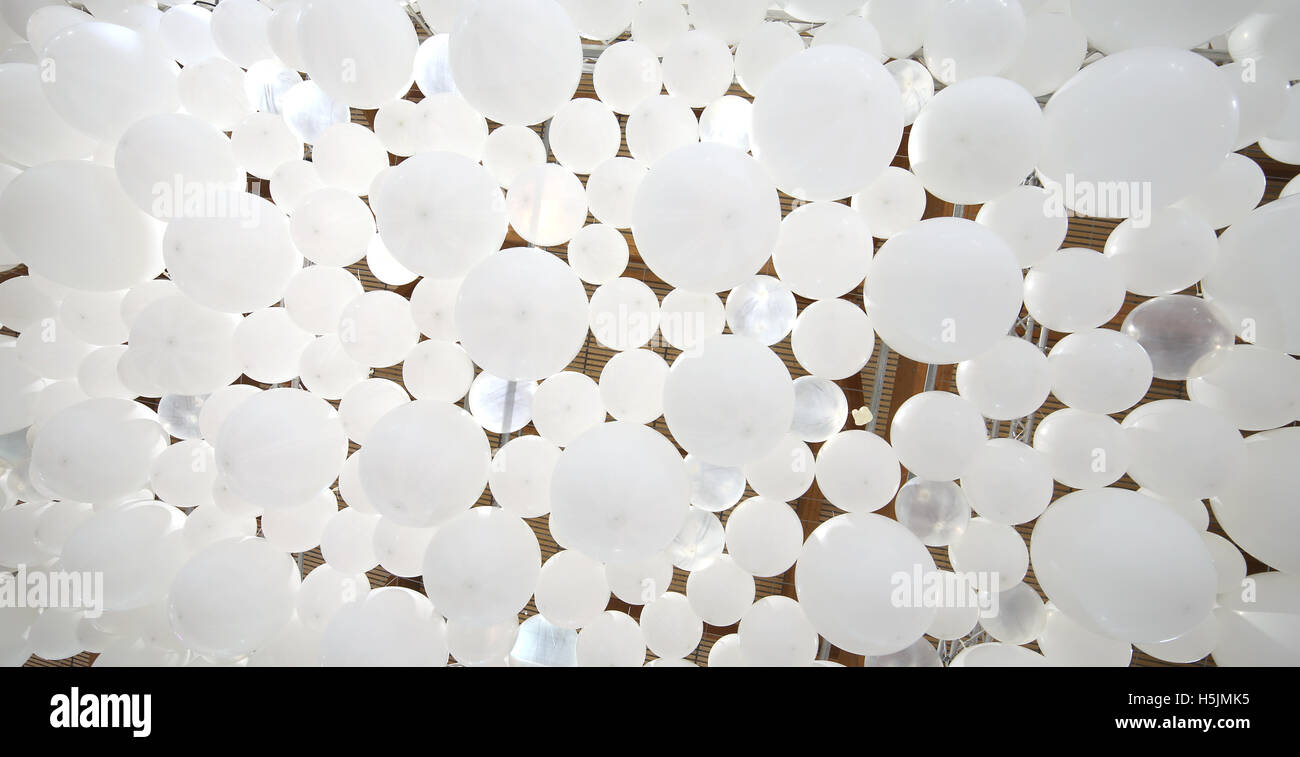 many big white balloons hanging from the ceiling during a ceremony and ...