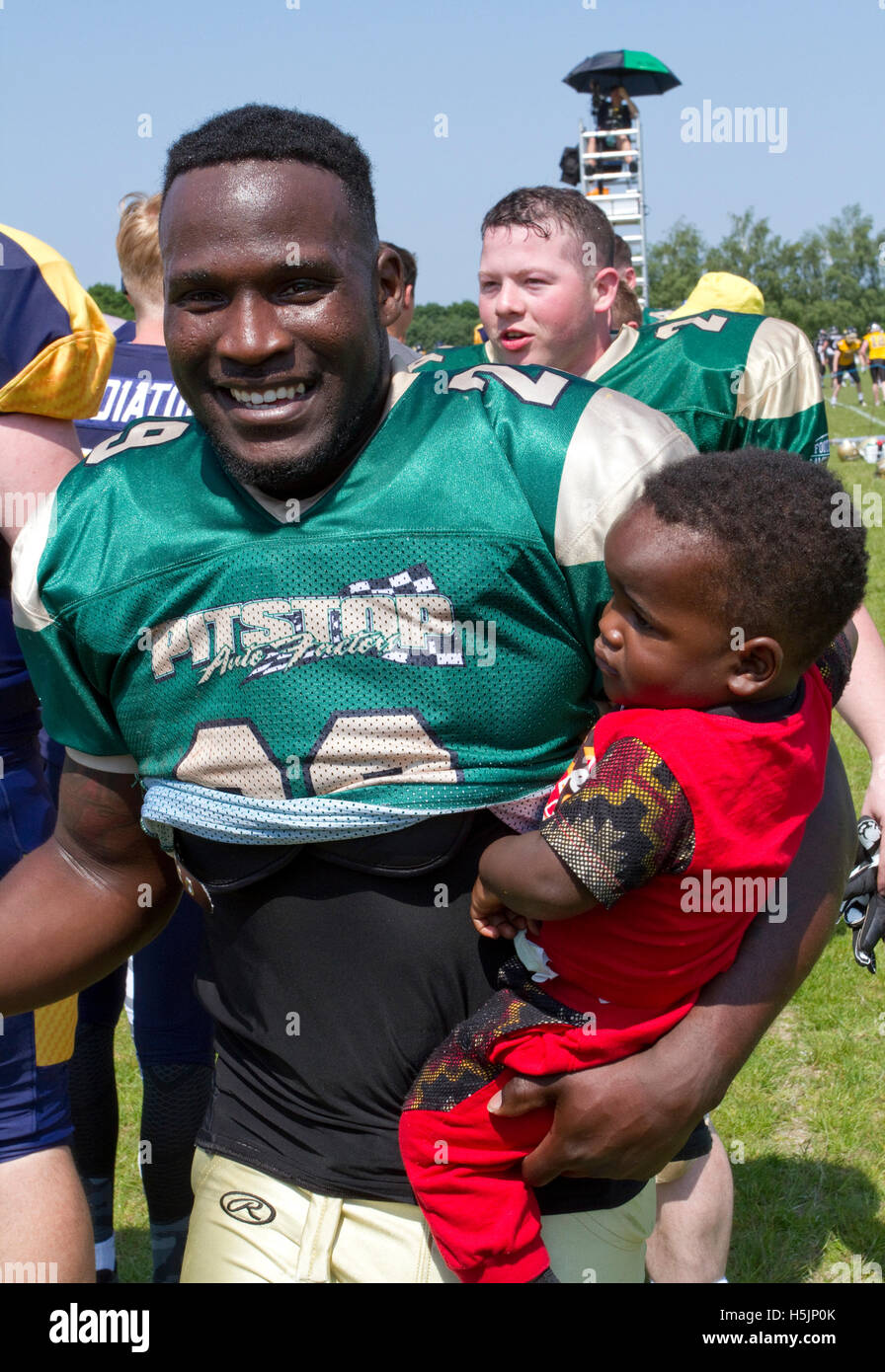 African American footballer holding baby son smiles at camera Stock ...