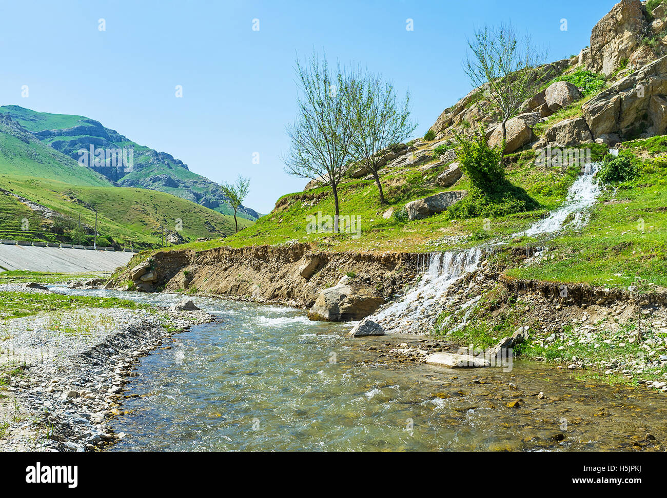 The small stream meets the mountain river in valley between Zarafshan ...