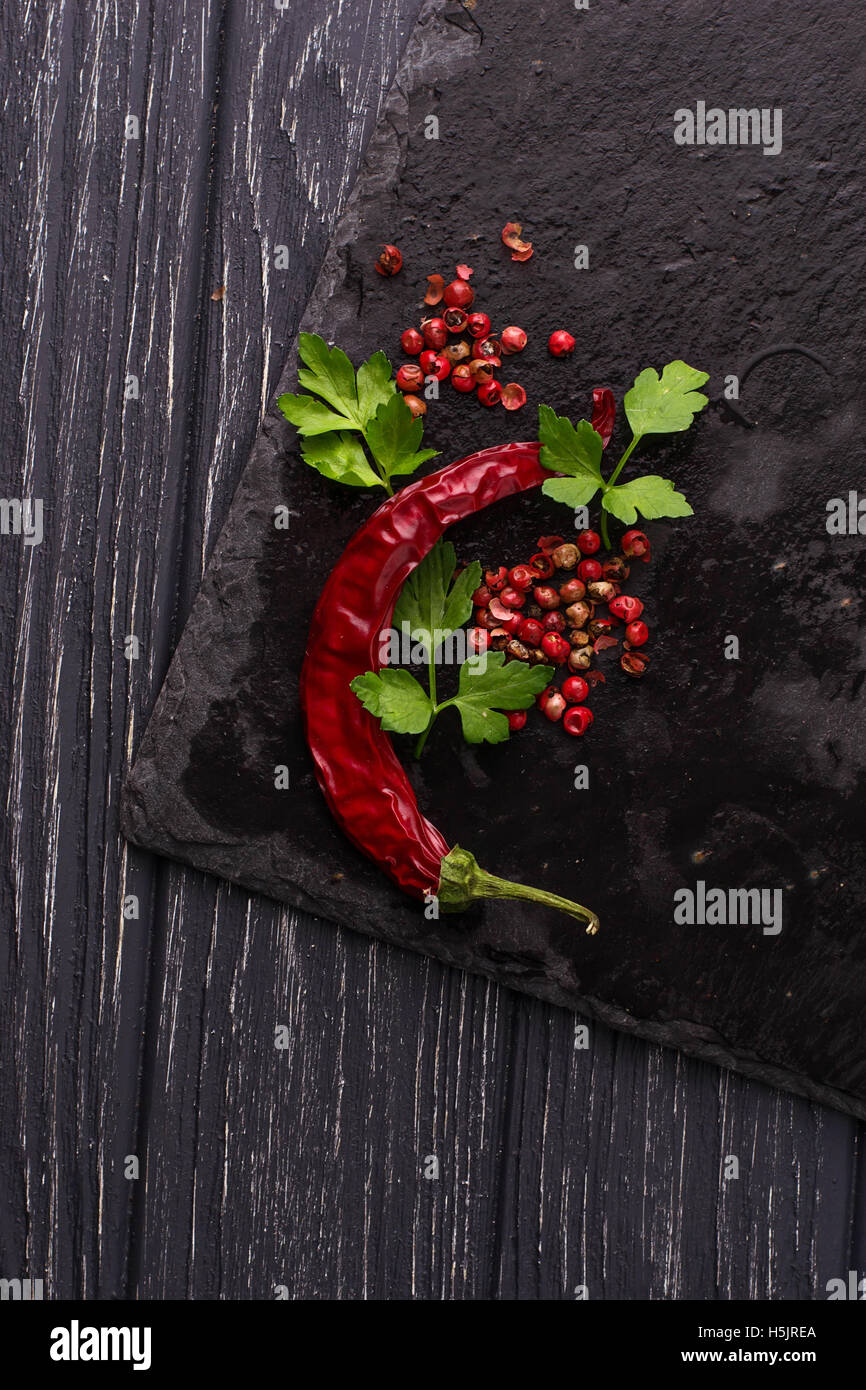 Chili peppers and rose pepper on slate background. Selective focus ...